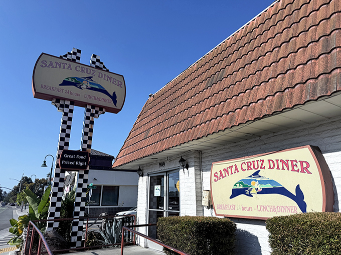 The iconic checkered sign beckons hungry travelers like a lighthouse for the famished. Classic California diner architecture at its finest.