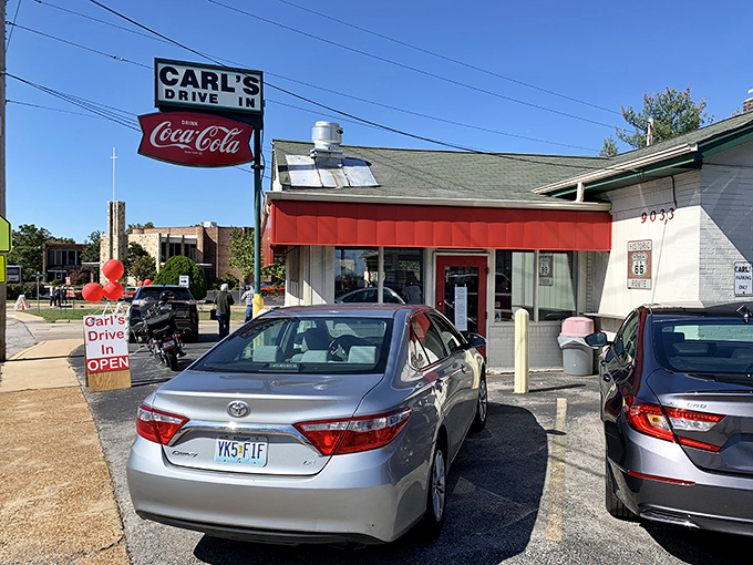 The classic red-awninged exterior of Carl's Drive-In stands as a Route 66 time capsule, beckoning hungry travelers with promises of nostalgia and root beer.