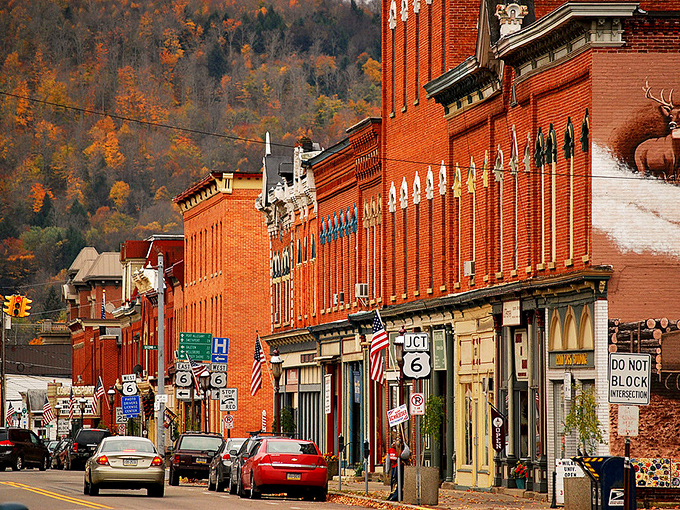 Main Street Coudersport in autumn glory &ndash; where brick buildings stand like sentinels against a backdrop of hills ablaze with fall foliage. Small-town America at its most photogenic. 