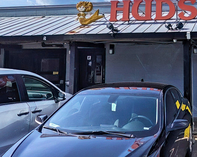 The iconic red Hudson's sign welcomes hungry visitors like a lighthouse beckoning seafood lovers to safe harbor. No fancy frills, just the promise of ocean-fresh delights.