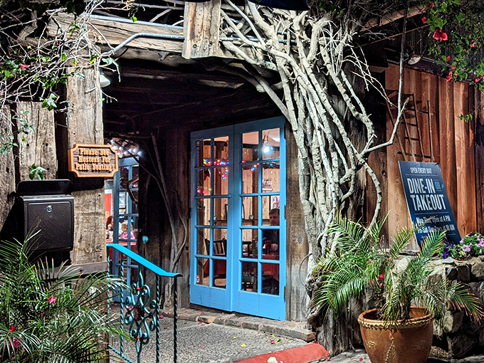 The entrance to Aunt Chilada's feels like stepping into a secret garden oasis, with bougainvillea cascading over rustic wooden beams and stone foundations.