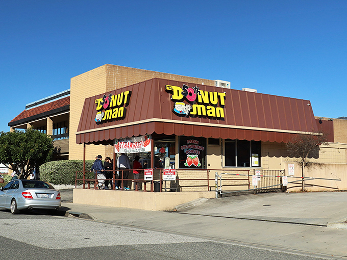 The iconic yellow and brown exterior of The Donut Man stands as a beacon of sweetness on Route 66, drawing pilgrims from across Southern California.