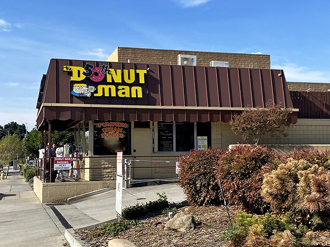 The iconic yellow and brown exterior of The Donut Man stands as a beacon of sweetness on Route 66, drawing pilgrims from across Southern California.