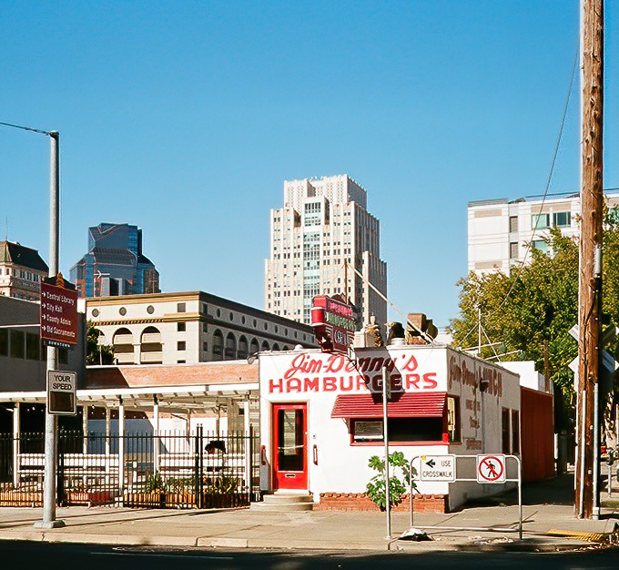 The little diner that could! Jim Denny's stands proudly amid Sacramento's skyline, its vintage red-and-white charm a defiant throwback to simpler times.