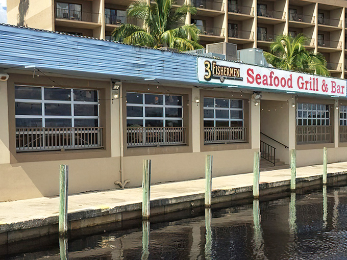 The blue-roofed waterfront gem beckons like a siren song, promising seafood treasures where the Caloosahatchee River meets your appetite.