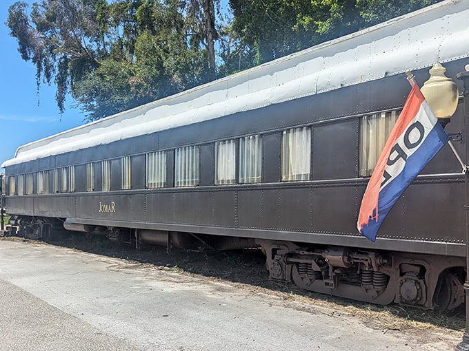 The vintage Pullman car "Jomar" stands proudly in Sarasota, its sleek dark exterior and open flag inviting curious diners to step back in time.