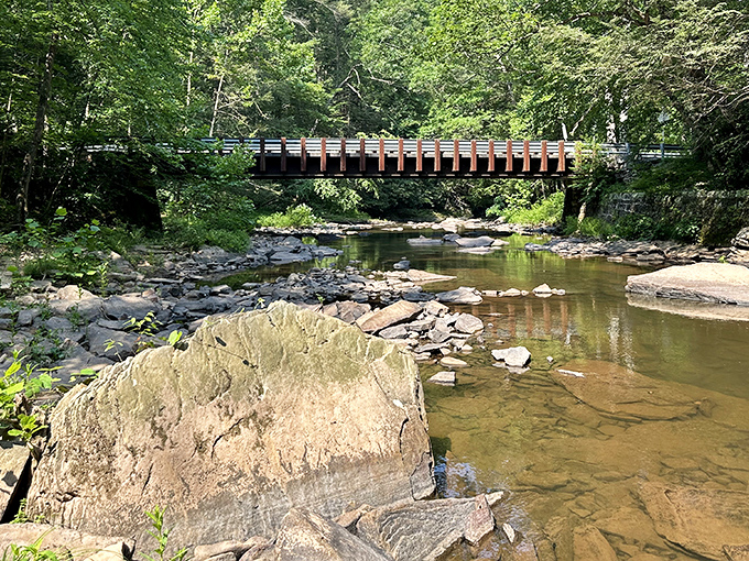 Nature's perfect postcard moment: a rustic wooden bridge spans the crystal-clear waters of Great Trough Creek, inviting adventurers to cross into Pennsylvania's best-kept secret.