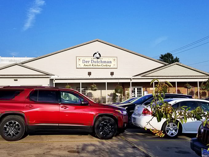 The welcoming white exterior of Der Dutchman stands like a beacon of comfort food in Walnut Creek, where hanging flower baskets add splashes of color to Amish simplicity.