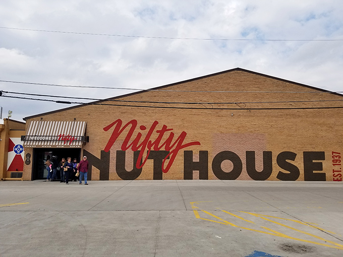 The brick facade of Nifty Nut House beckons like a siren song to sugar enthusiasts. That red script logo promises sweet adventures within.