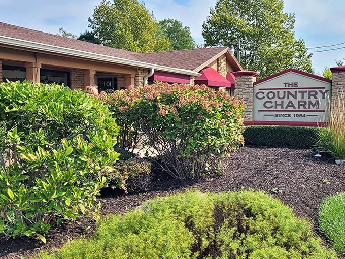 The stone sign stands like a culinary lighthouse, guiding hungry travelers to Country Charm's doorstep since 1984. Those burgundy awnings promise comfort before you even step inside.