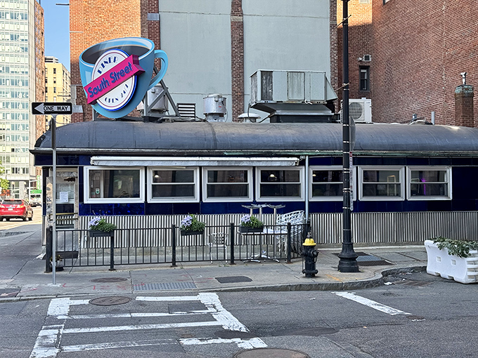 The iconic blue coffee cup sign beckons hungry souls to South Street Diner like a neon lighthouse in Boston's brick-lined Leather District.