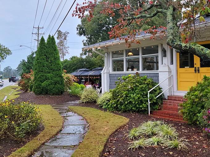 The charming cottage exterior with its signature yellow door promises culinary magic within. Like finding a secret garden that happens to serve incredible biscuits.