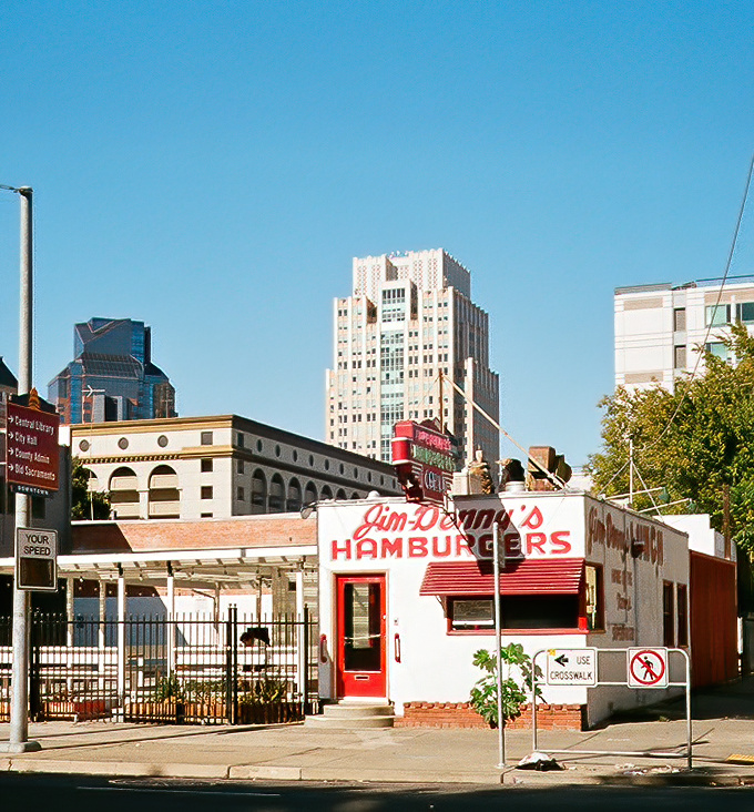 The little diner that could! Jim Denny's stands proudly amid Sacramento's skyline, its vintage red-and-white charm a defiant throwback to simpler times.
