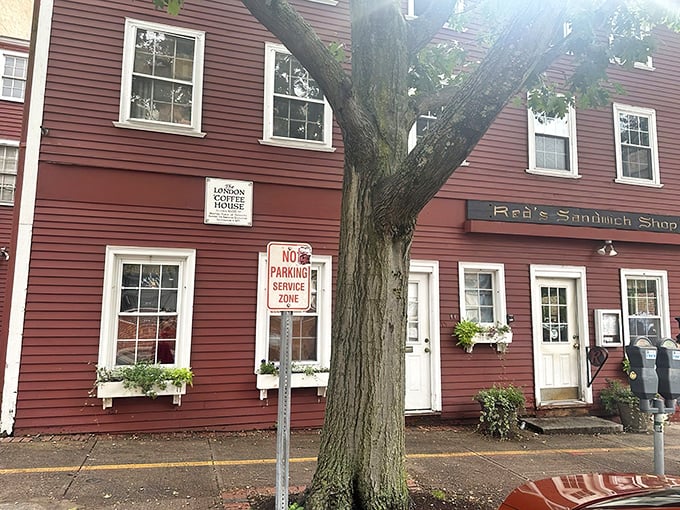 The iconic crimson colonial exterior of Red's Sandwich Shop stands as proudly in Salem as Paul Revere once did, beckoning hungry visitors with historical charm.