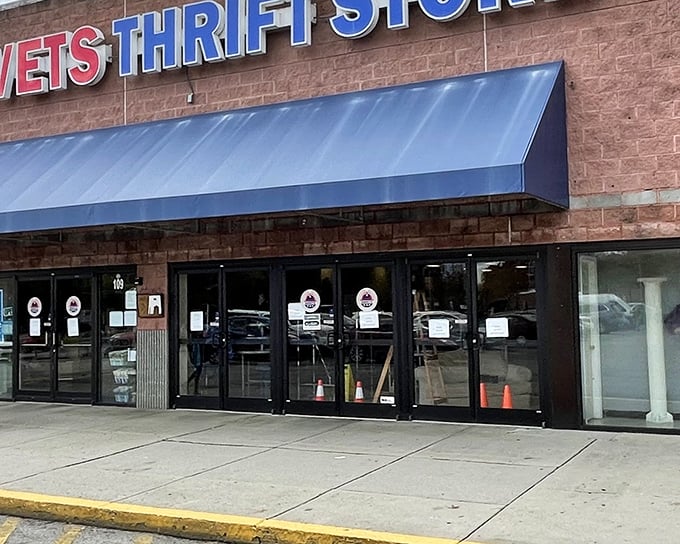 The blue awning beckons like a portal to bargain paradise. AMVETS Thrift Store's unassuming exterior hides treasures waiting to be discovered.