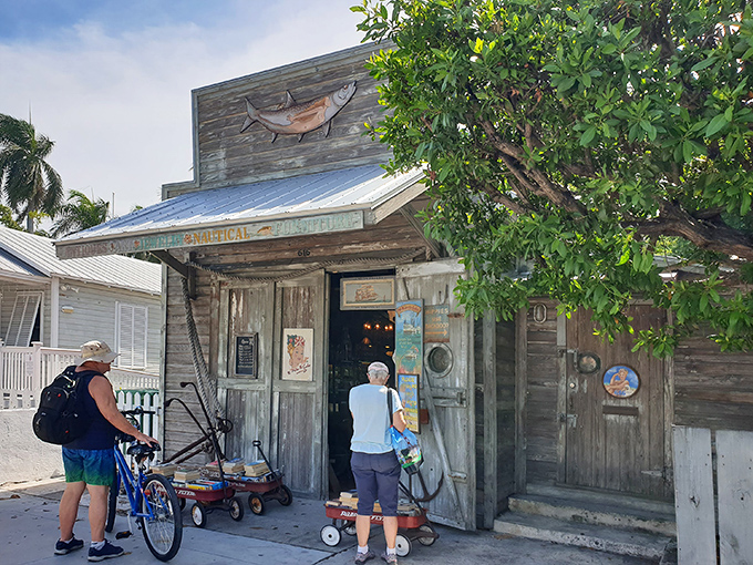 The unassuming exterior of 90 Miles To Cuba stands like a weathered sentinel of Key West history, colorful nautical flags beckoning curious travelers to explore its treasures.