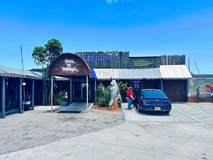 The weathered wooden exterior of The Old Fish House screams "authentic Florida" with its blue signage and that charming manatee statue standing guard at the entrance. 