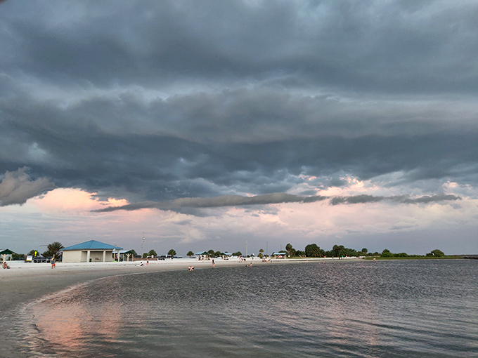 Dramatic storm clouds create a moody backdrop over Fort Island Beach, where the Gulf waters meet pristine shoreline in a perfect Florida moment.