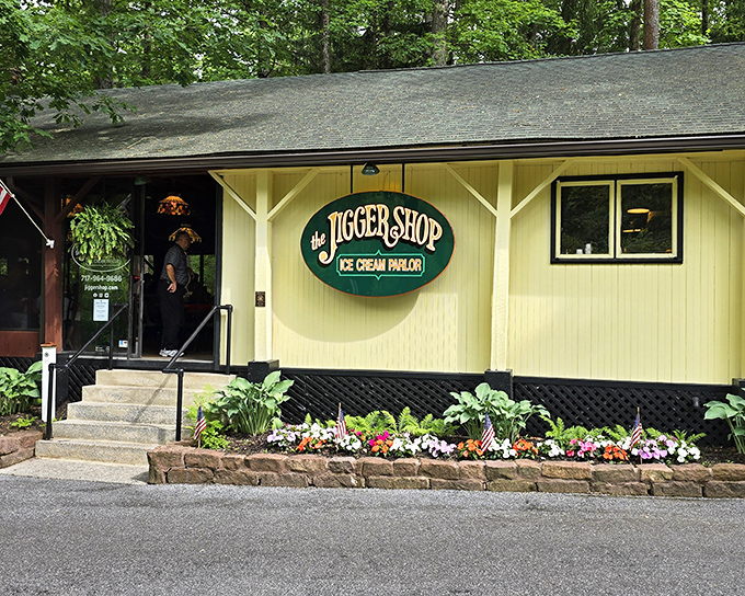The yellow clapboard exterior of The Jigger Shop beckons like an old friend, complete with hanging plants and that iconic green sign promising sweet memories ahead.