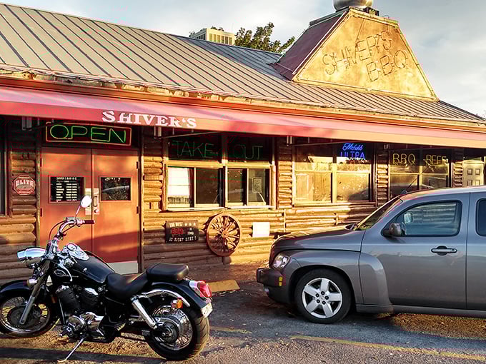 That neon sign isn't just advertising &ndash; it's a lighthouse for hungry souls. The log cabin exterior promises authentic barbecue without pretension.