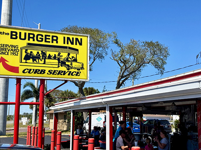 The bright yellow sign stands like a time machine on US-1, promising curb service and burger bliss since Eisenhower was signing legislation. 