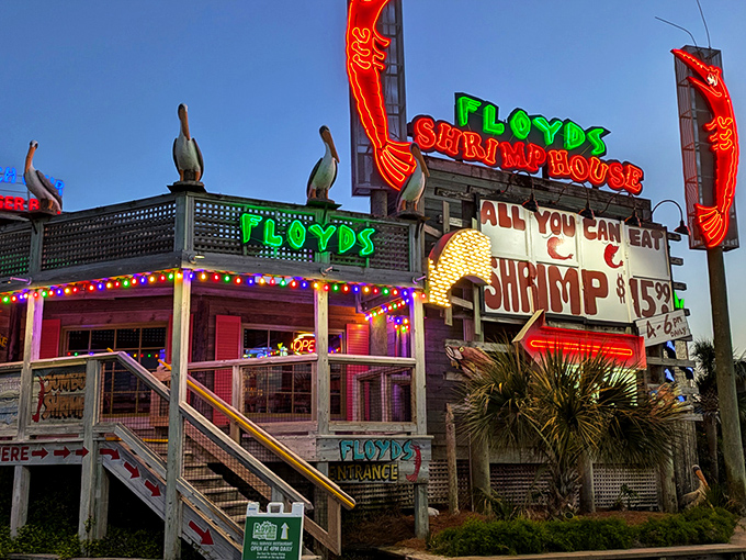 Floyd's neon sign blazes against the twilight sky like a lighthouse for hungry sailors, complete with pelican sentinels standing guard over shrimp paradise.