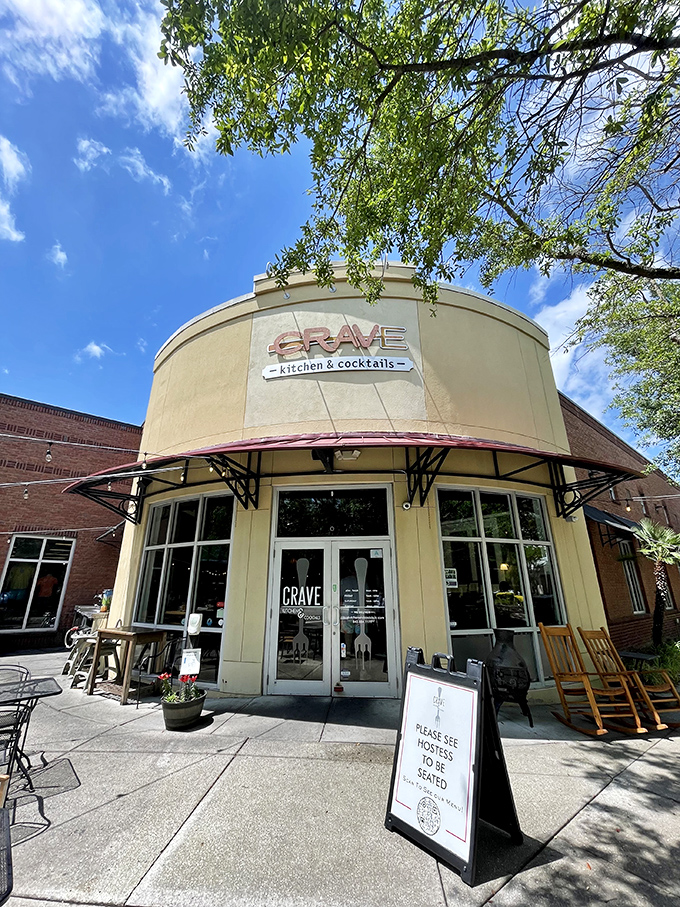 The curved facade of Crave beckons like a cheesy siren call. Those red umbrellas promise refuge from both sun and boring meals.