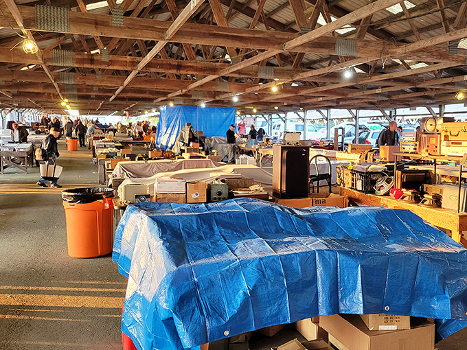 Treasure hunters navigate the cavernous barn-like structure where decades of history await discovery beneath rustic wooden beams and warm lighting.