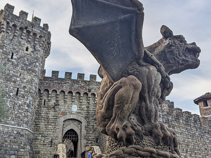 The castle entrance guarded by a stone gargoyle that looks like it might come alive after hours. Medieval fantasy meets California sunshine in this imposing entryway.
