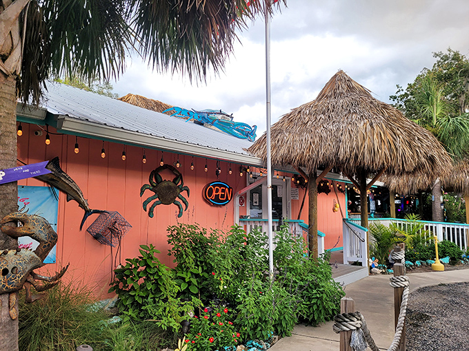 The coral-colored exterior of Kathi's Krab Shack beckons like a tropical mirage, complete with thatched roof and a giant crab announcing seafood paradise awaits.
