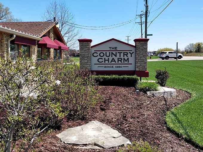 The stone sign stands like a culinary lighthouse, guiding hungry travelers to Country Charm's doorstep since 1984. Those burgundy awnings promise comfort before you even step inside.