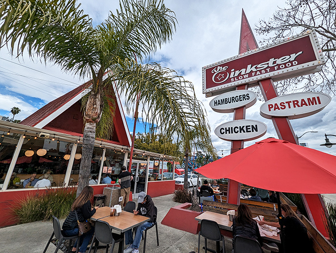 The iconic A-frame building beckons like a red-roofed temple of deliciousness, complete with retro signage that doesn't mince words: hamburgers, pastrami, chicken.