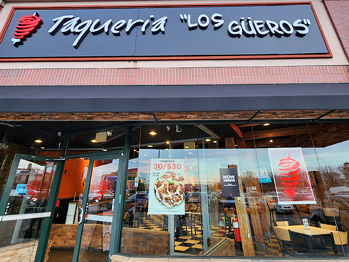 The iconic black sign with white lettering and red spiral logo beckons hungry travelers like a lighthouse for those lost in a sea of mediocre Mexican food.