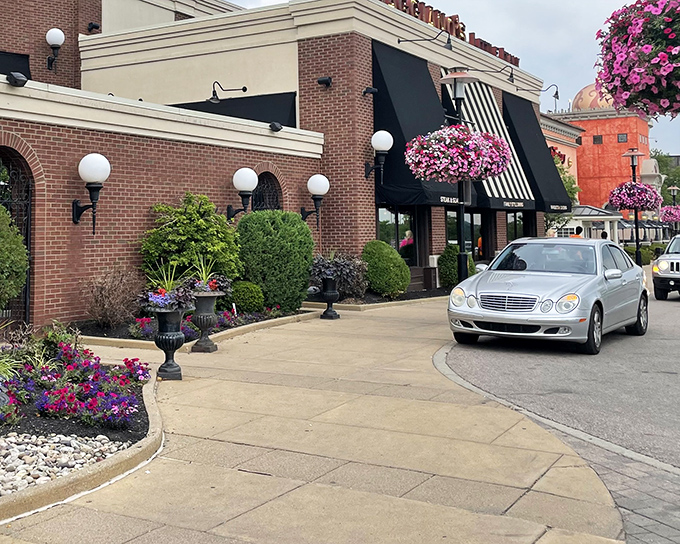 The welcoming brick exterior of Maggiano's Little Italy, where hanging flower baskets and classic awnings promise Italian comfort before you even step inside.