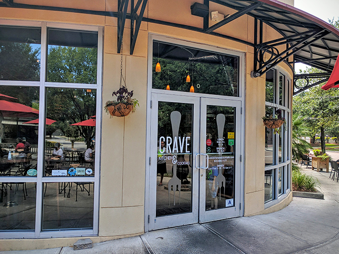 The curved facade of Crave beckons like a cheesy siren call. Those red umbrellas promise refuge from both sun and boring meals.