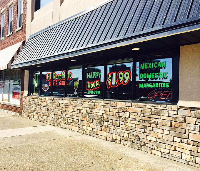 The vibrant storefront of El Ranchito glows like a beacon of culinary promise, its colorful signage and stone facade practically shouting "authentic Mexican food happens here!"