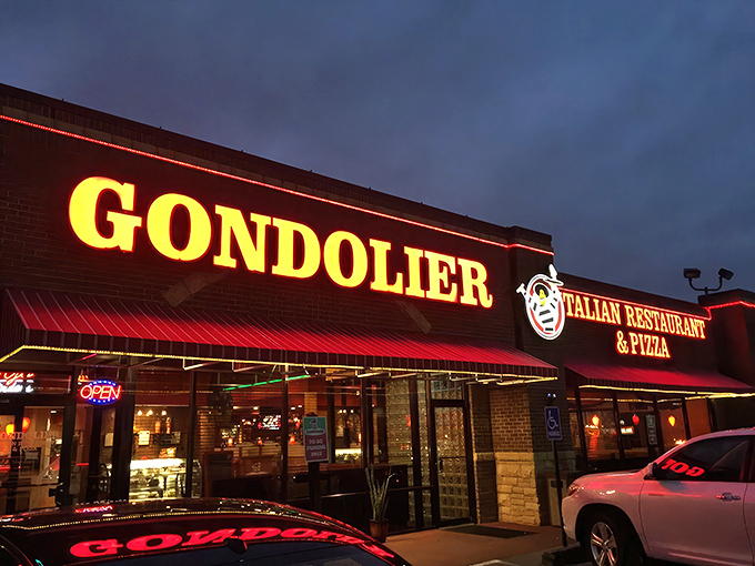 The bold red Gondolier sign beckons like a lighthouse for pasta pilgrims, promising Italian comfort under those distinctive striped awnings.