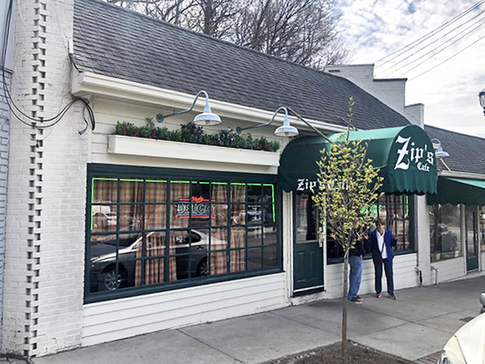 The unassuming white brick exterior of Zip's Cafe, with its signature green awning, proves that culinary greatness rarely needs flashy advertising.
