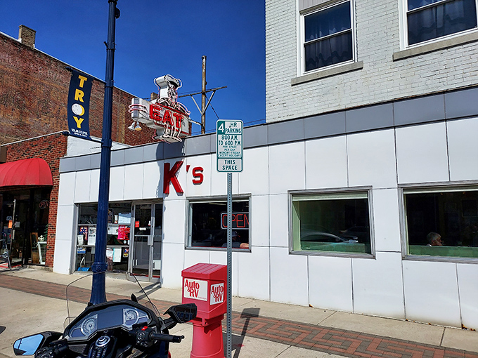 The iconic white-tiled exterior of K's Hamburger Shop stands like a time capsule on Troy's Main Street, complete with a cheerful chef proudly hoisting his burger creation.