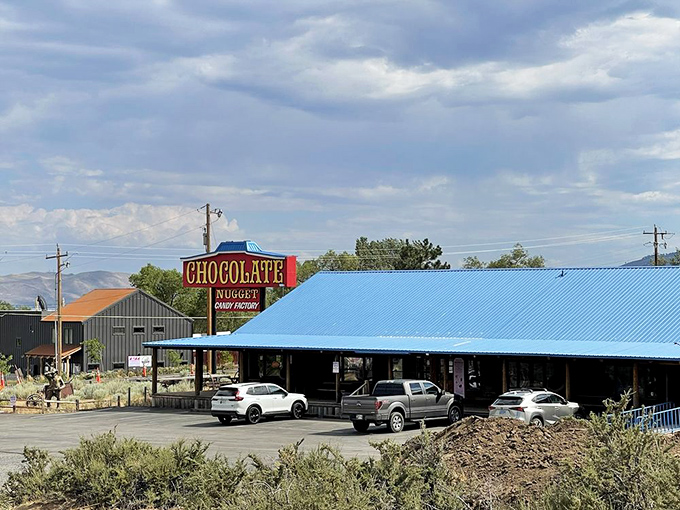 The rustic log cabin exterior of Chocolate Nugget beckons like a sweet mirage in the Nevada desert, complete with picnic tables for immediate sugar-rush recovery.
