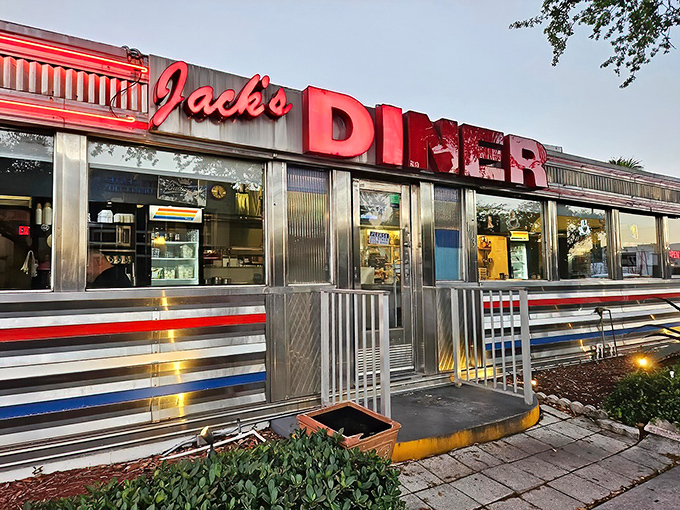 The gleaming chrome exterior and bold red signage of Jack's Hollywood Diner stands like a time capsule of American nostalgia, surrounded by Florida's lush tropical landscaping.