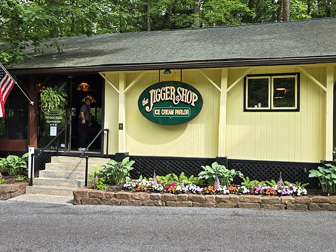 The yellow clapboard exterior of The Jigger Shop beckons like an old friend, complete with hanging plants and that iconic green sign promising sweet memories ahead.