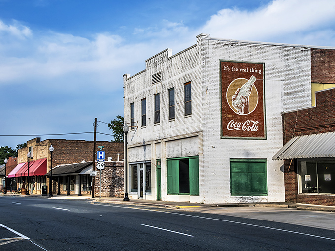 Sunlight hits the vintage white brick buildings as you stroll past a classic Coca-Cola mural in this charming, quiet downtown.