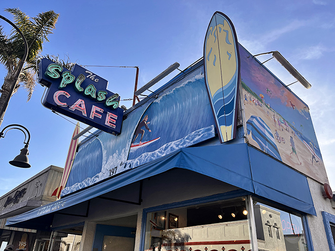 The iconic blue facade of Splash Cafe stands like a beacon of culinary hope on Pismo Beach's shoreline, complete with surfboard sentinel.