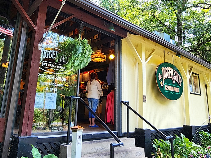 The yellow clapboard exterior of The Jigger Shop beckons like an old friend, complete with hanging plants and that iconic green sign promising sweet memories ahead.