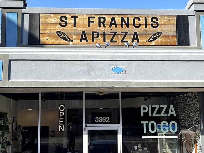 The wooden sign beckons like a secret handshake. Saint Francis Apizza's unassuming storefront hides pizza greatness behind glass doors on Erie Avenue.