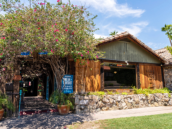 The entrance to Aunt Chilada's feels like stepping into a secret garden oasis, with bougainvillea cascading over rustic wooden beams and stone foundations.