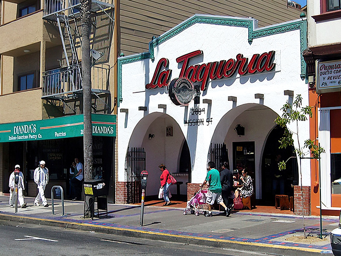 The iconic white facade with red lettering beckons like a culinary lighthouse. La Taqueria's modest exterior belies the extraordinary flavors waiting inside.