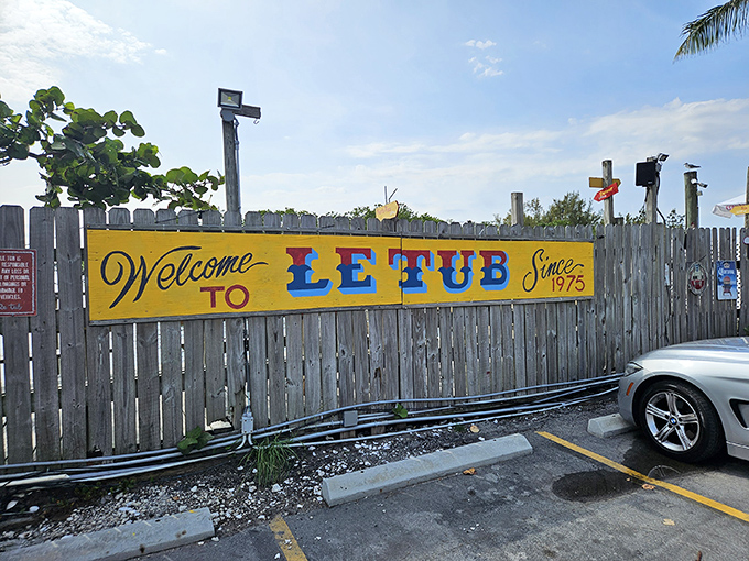 The unassuming wooden fence and yellow sign of Le Tub are Florida's version of a speakeasy entrance—secrets and seafood await behind these weathered boards.