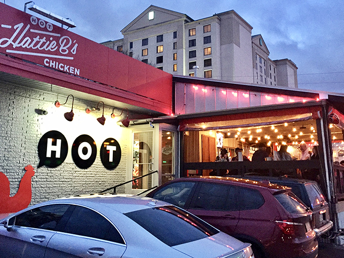 The iconic red awning of Hattie B's glows like a beacon of spicy salvation against the Nashville skyline. Hot chicken paradise awaits!